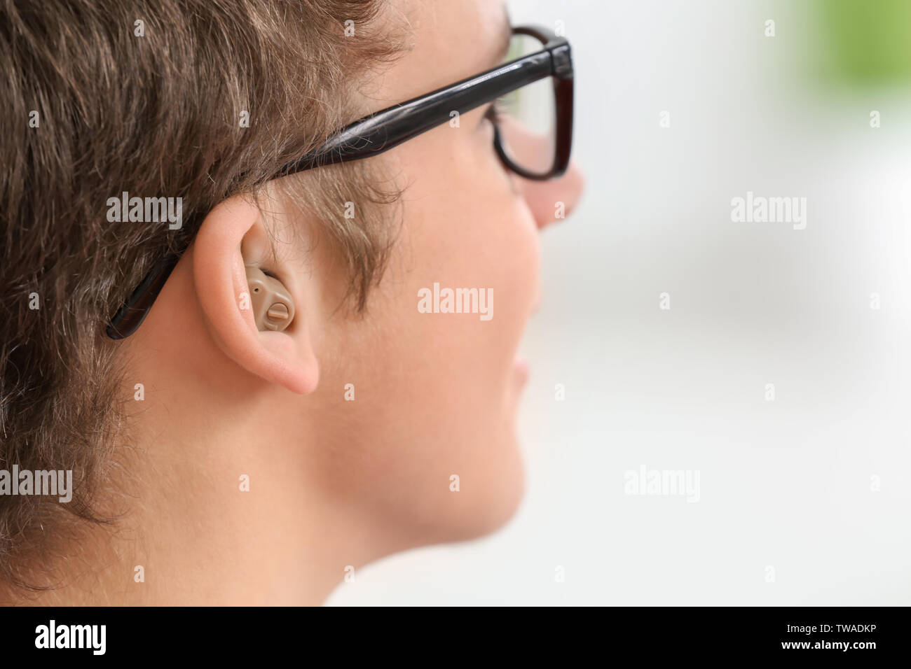 Teenage boy with hearing aid indoors Stock Photo - Alamy