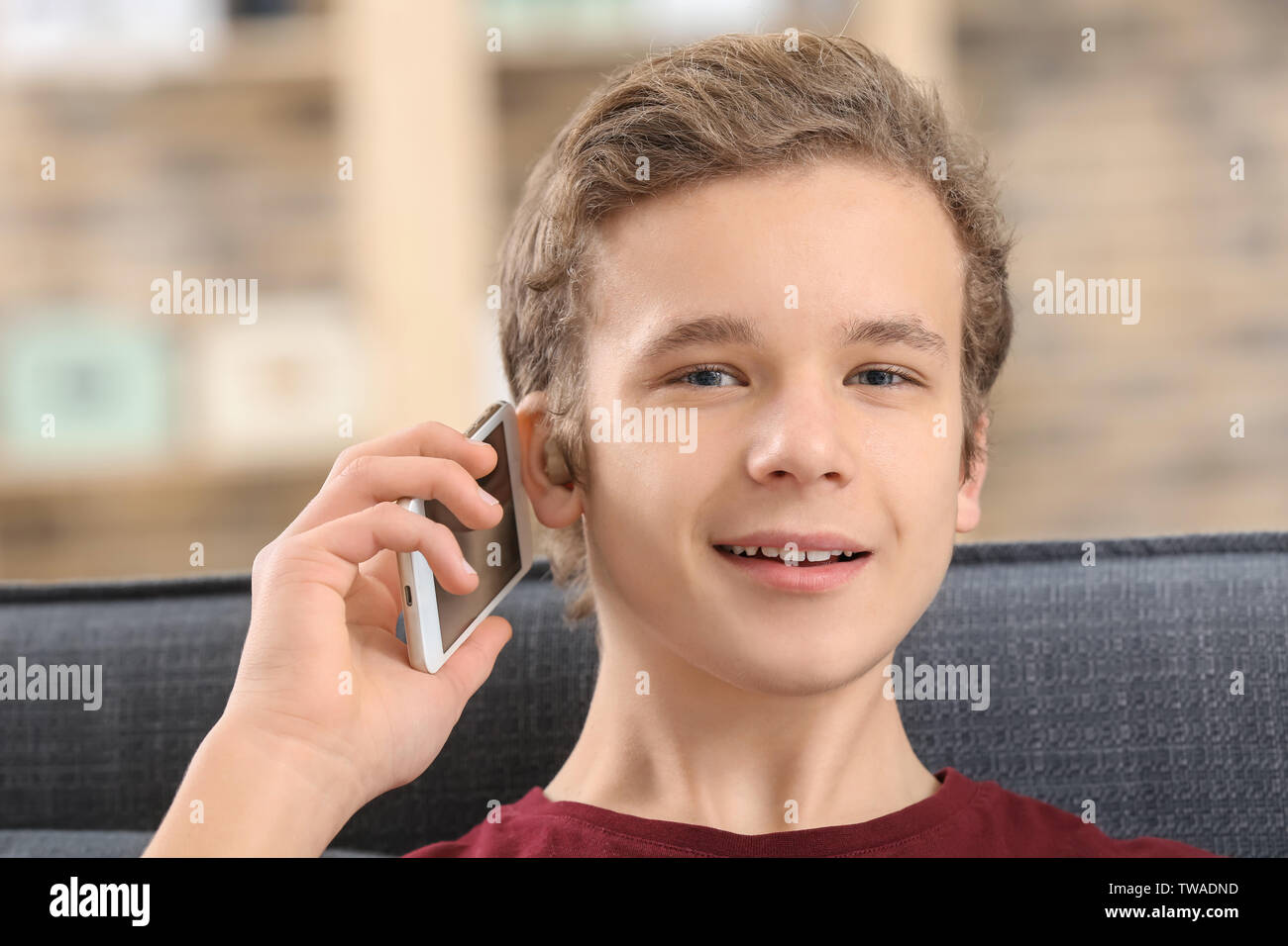 Teenage boy with hearing aid talking on phone indoors Stock Photo - Alamy