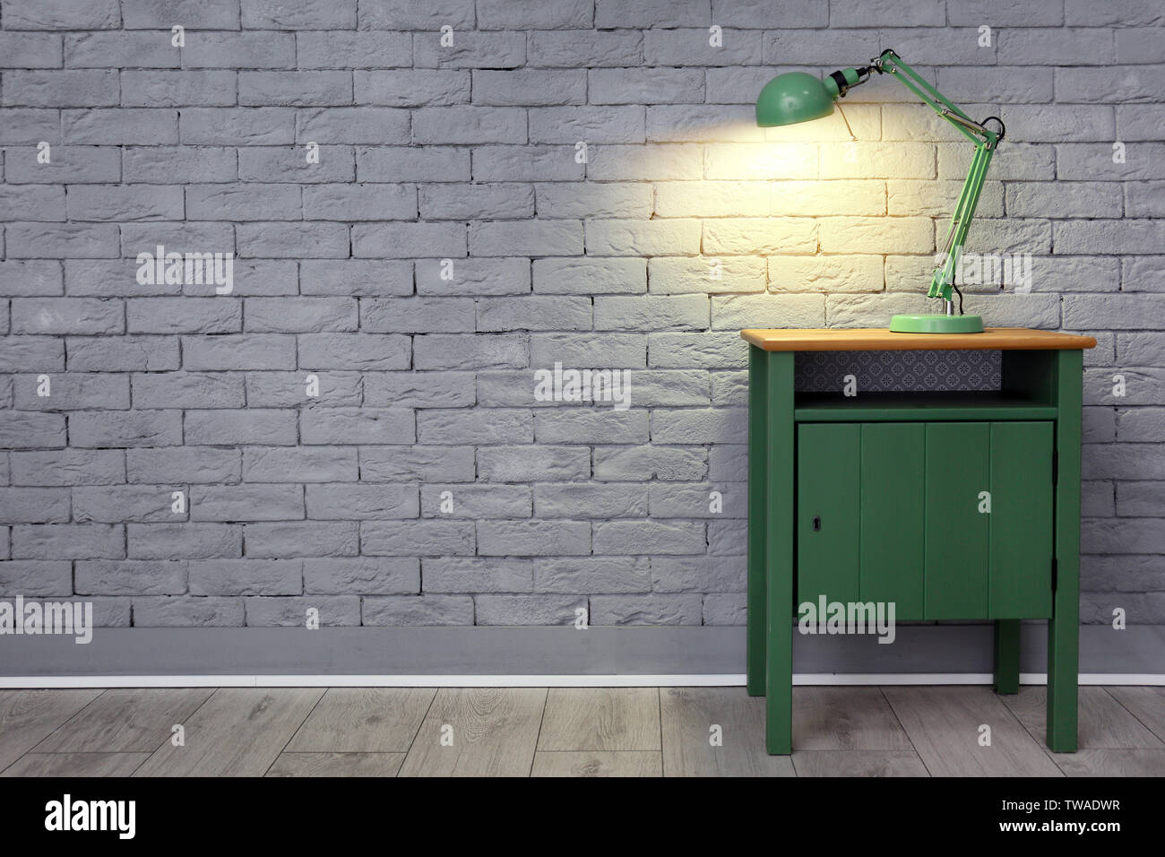 Lamp on stand near brick wall Stock Photo - Alamy