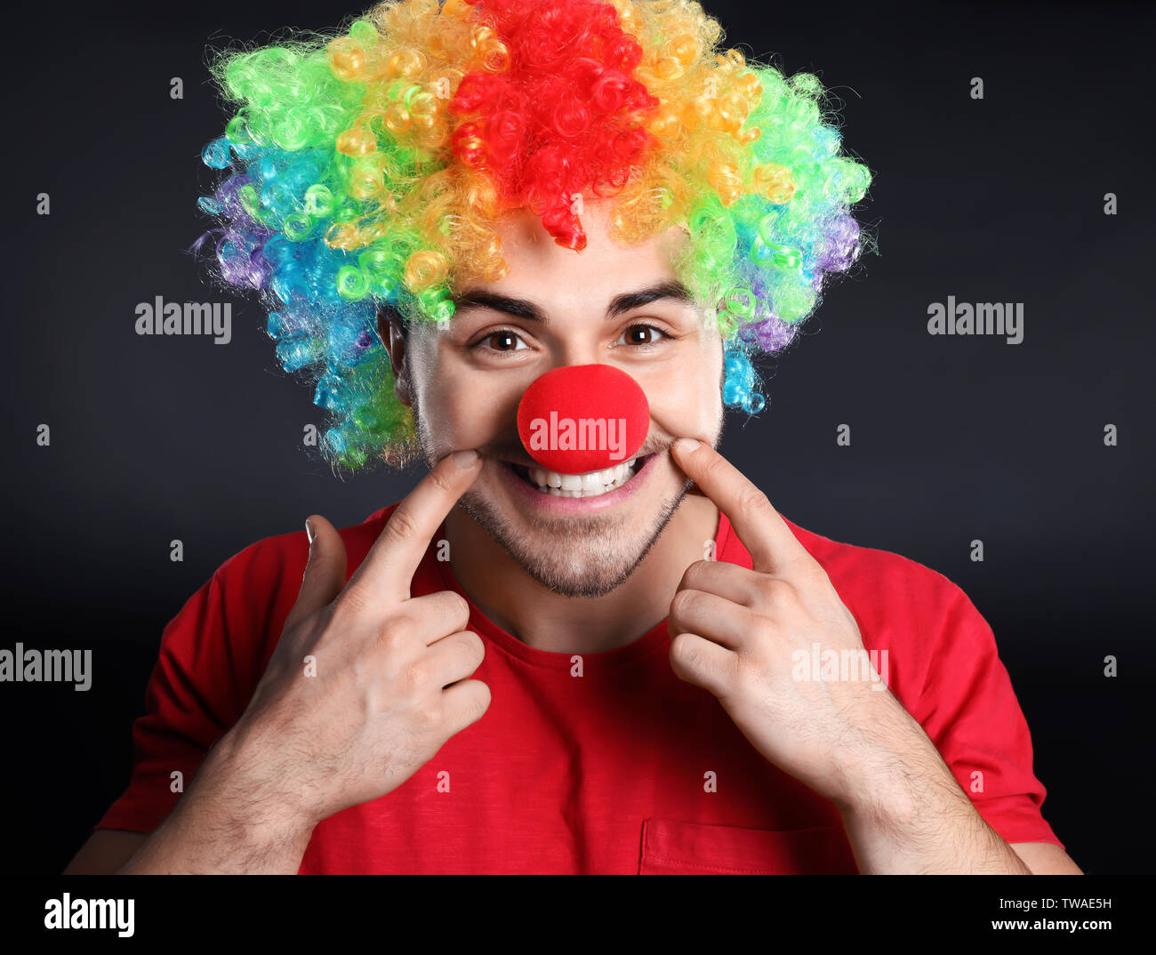 Young man in funny disguise on grey background. April fool's day ...