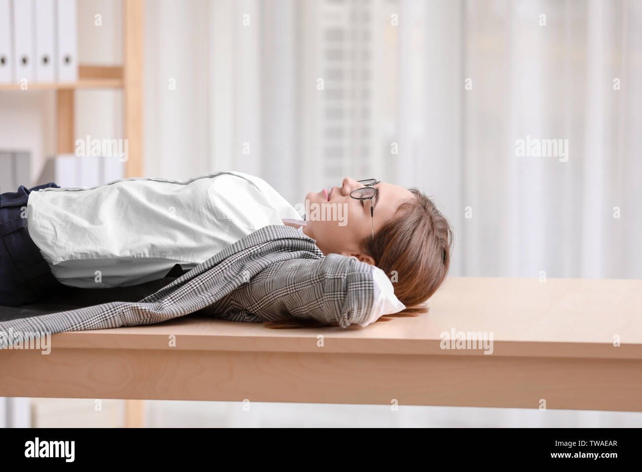 Young woman lying on table in office Stock Photo - Alamy