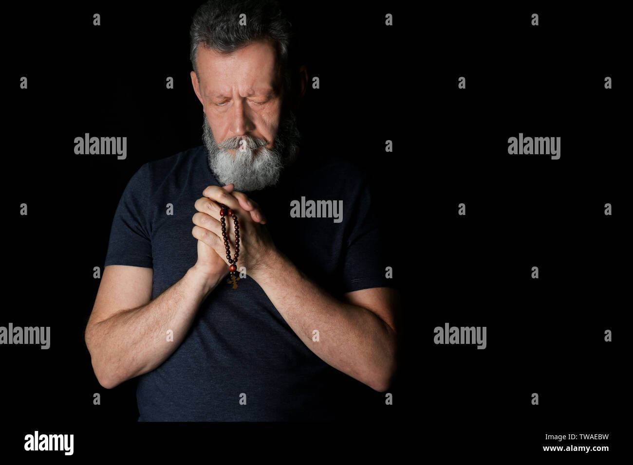 Religious senior man praying on black background Stock Photo - Alamy