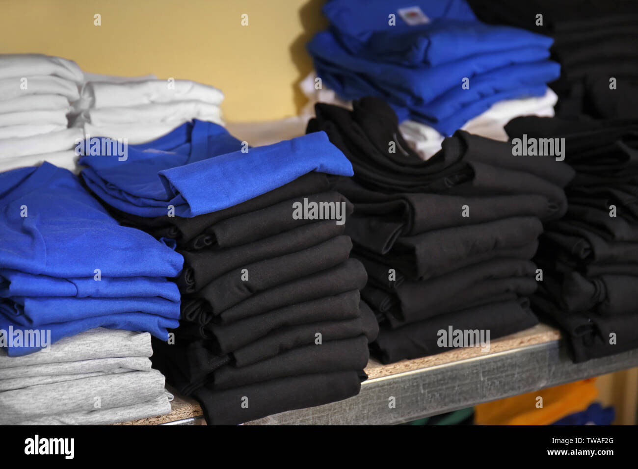 Stacks of t-shirts prepared for printing on shelf Stock Photo - Alamy