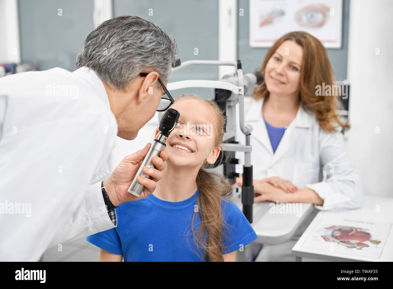 Girl checking vision in laboratory. Child sitting and looking at camera ...