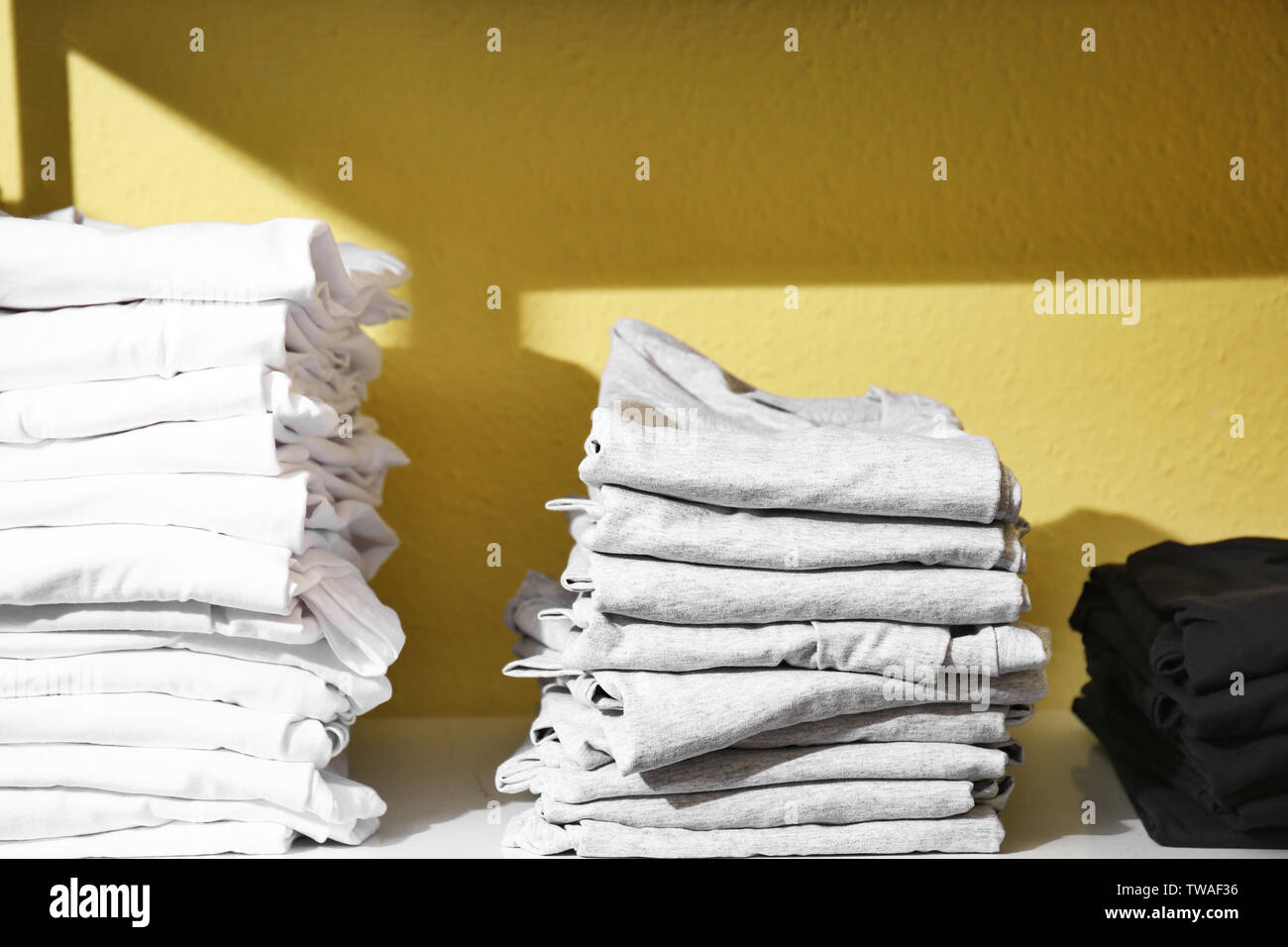 Stacks of white t-shirts prepared for printing on shelf Stock Photo - Alamy