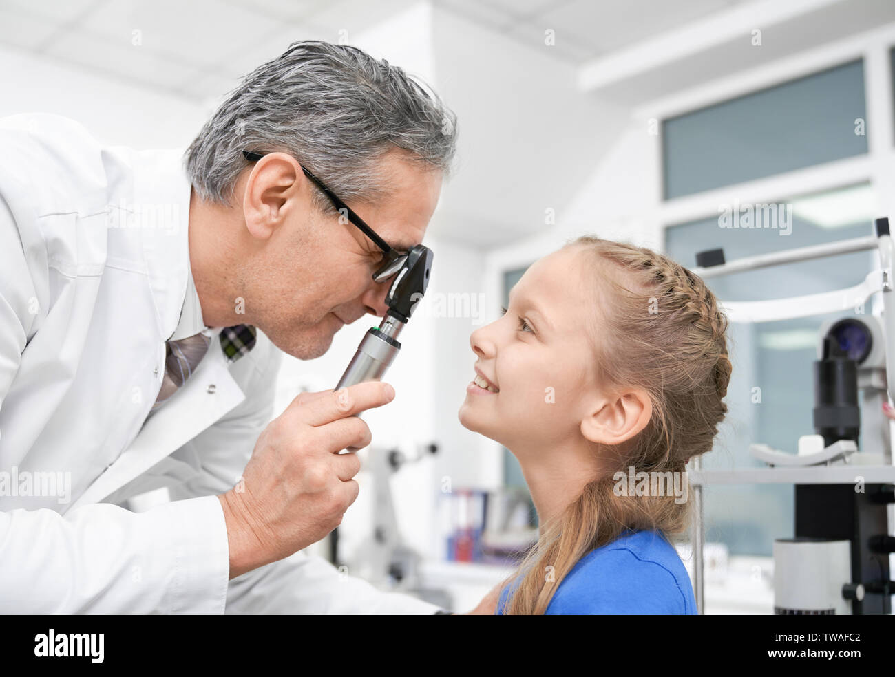 Side view of professional male oculist testing eye sight with special ...