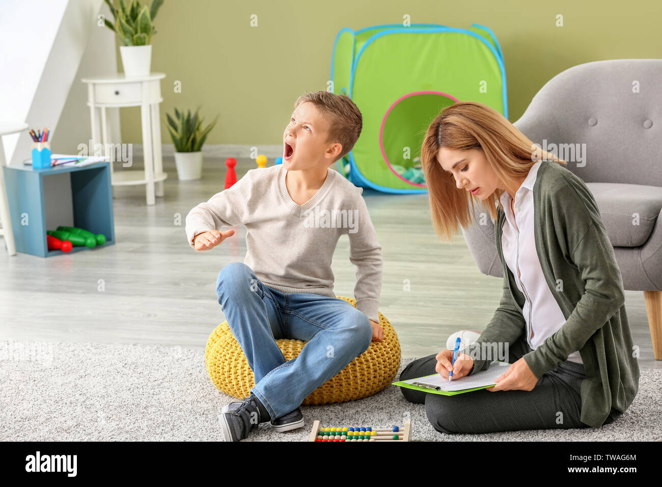 Female psychologist working with boy suffering from autistic disorder ...