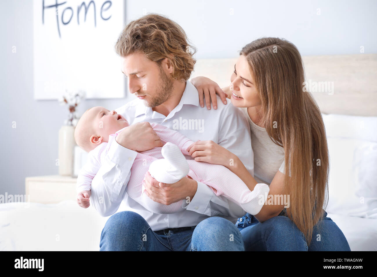 Happy parents with cute little baby at home Stock Photo - Alamy