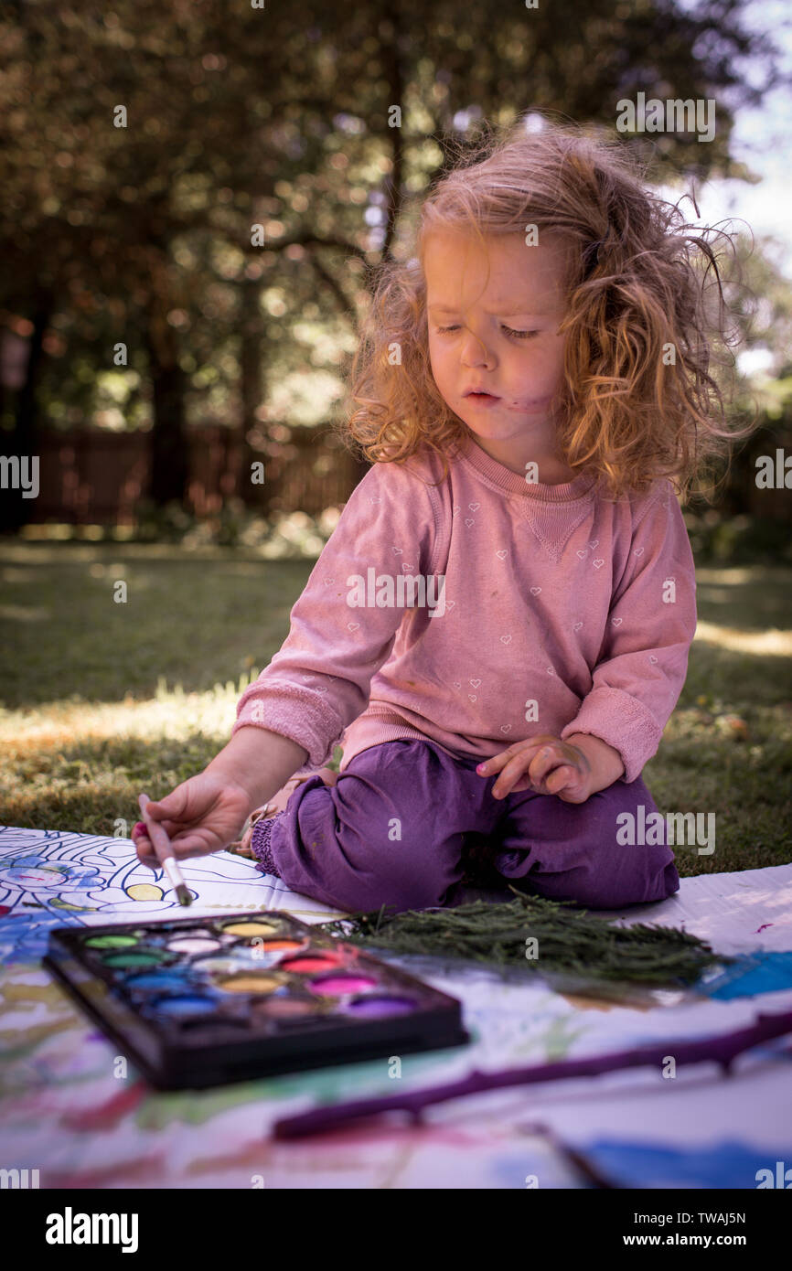Little girl creating art, painting a drawing with water colors and ...