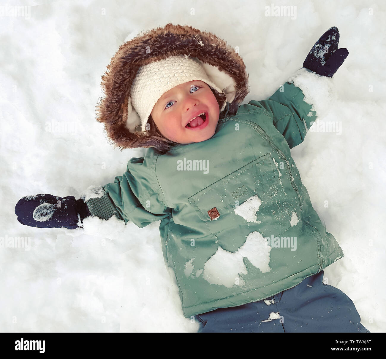 Smiling, happy, cute child with blue eyes enjoying winter and making ...
