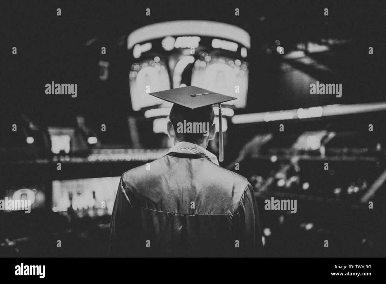 Black and white back shot of a student graduating in a big hall wearing ...