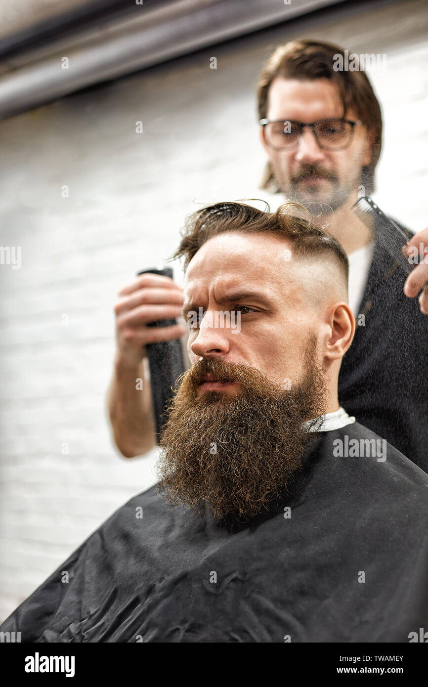 Brutal guy in modern Barber Shop. Hairdresser makes hairstyle a man ...