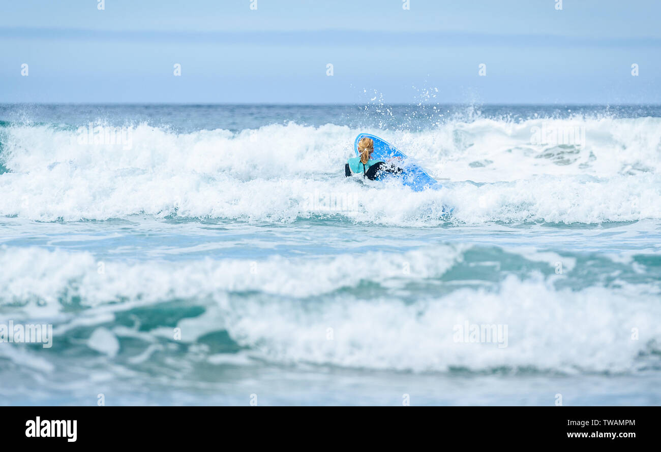 Surfer woman with surfboard is walking and watching the waves. Girl in ...