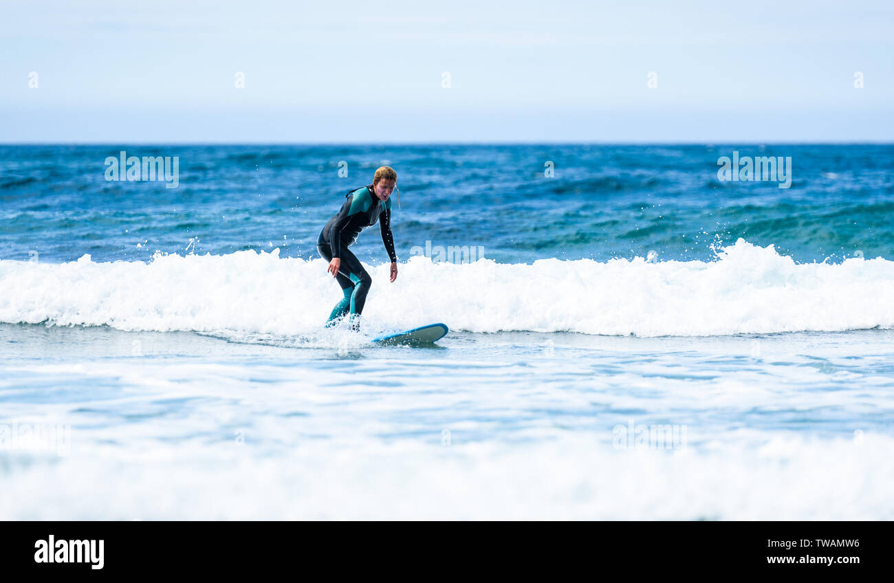 Surfer girl surfing with surfboard on waves in Atlantic ocean. Woman in ...