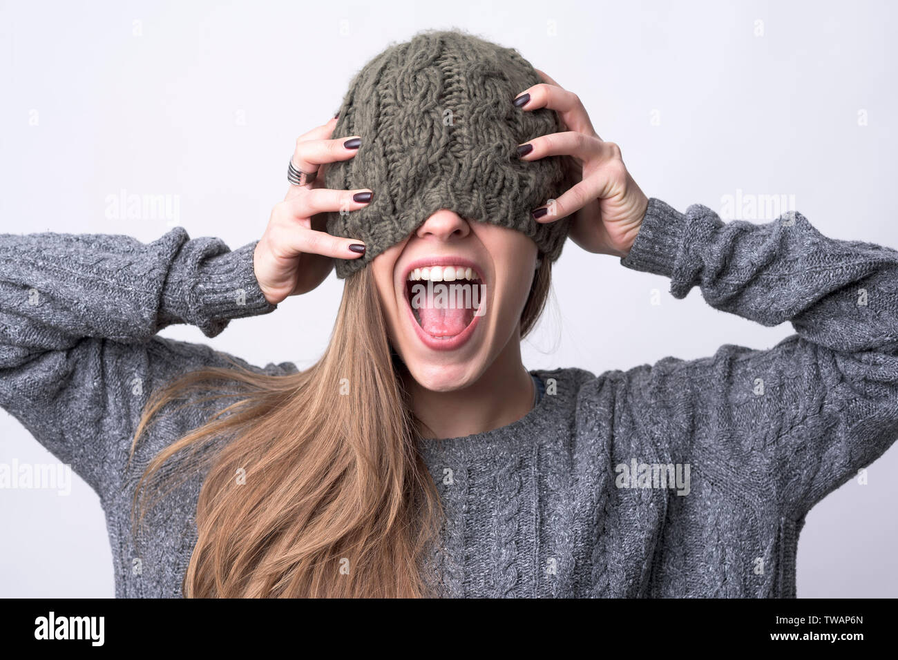 Conceptual portrait of young woman screaming with cap over her eyes and ...