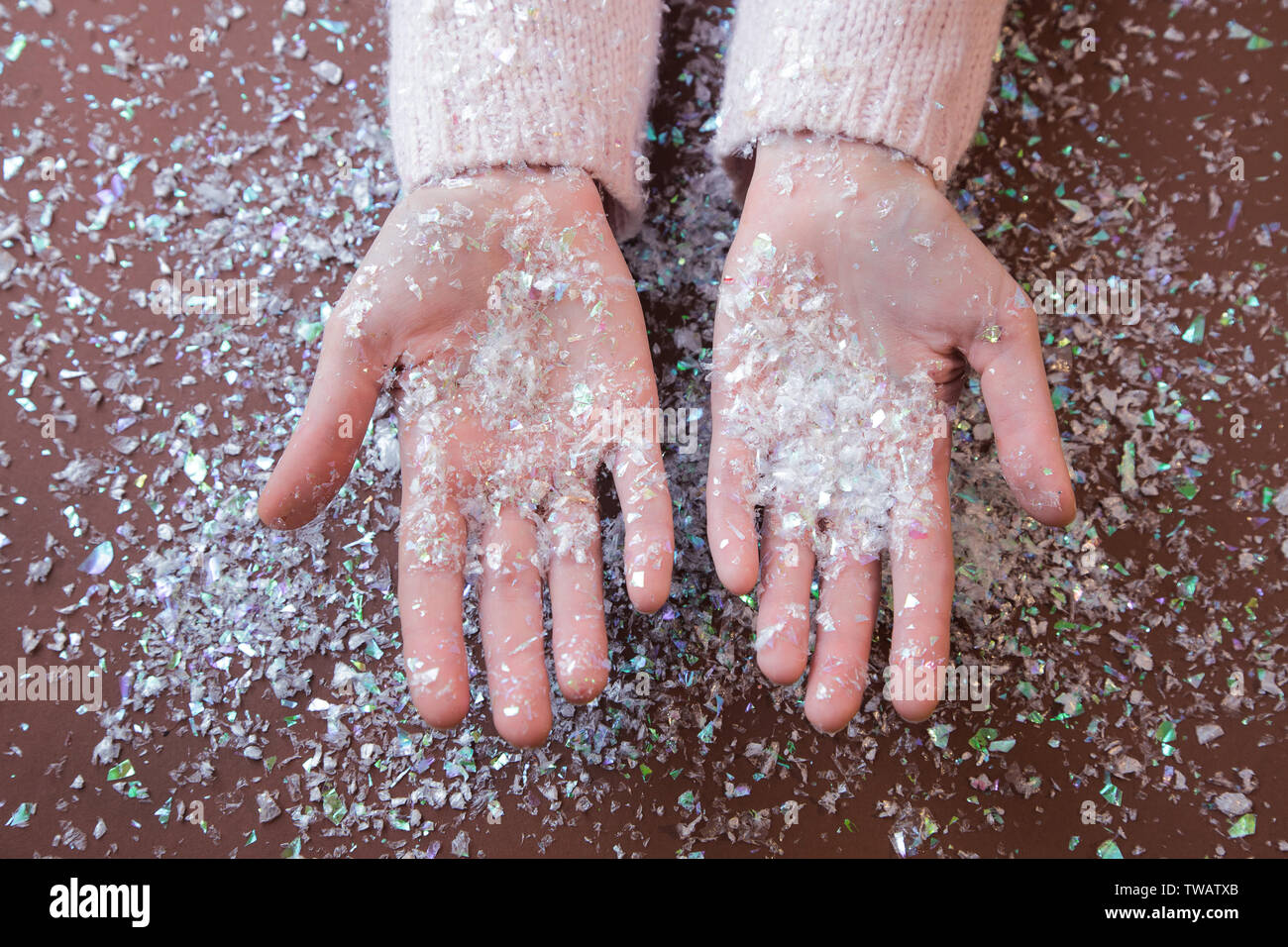 Female hands catch falling snow. Hands over a brown table with falling ...