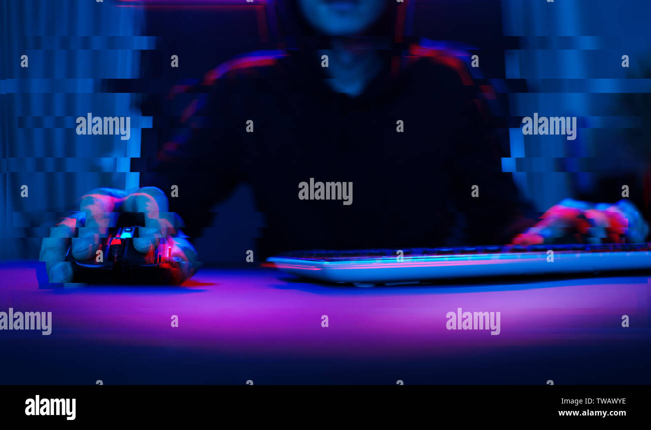 Hacker In The Hood Working With Computer Typing Text In Dark Room Image With Glitch Effect