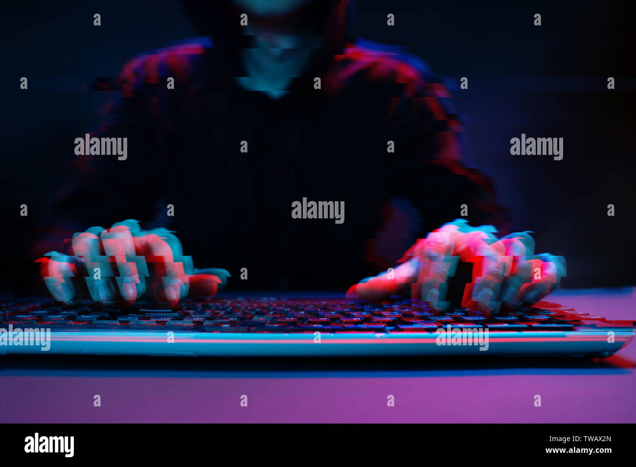 Hacker in the hood working with computer typing text in dark room ...