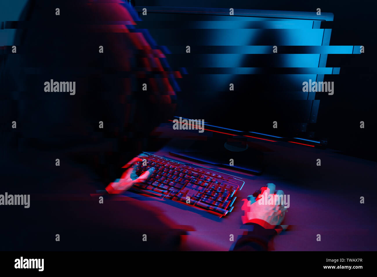 Hacker in the hood working with computer typing text in dark room. Image with glitch effect ...