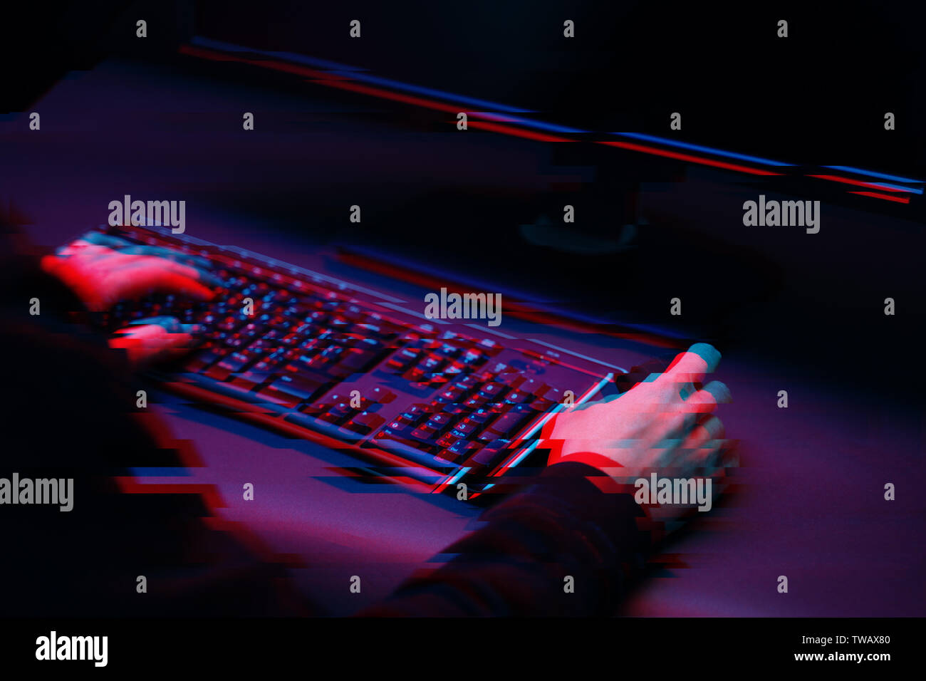 Hacker in the hood working with computer typing text in dark room. Image with glitch effect ...