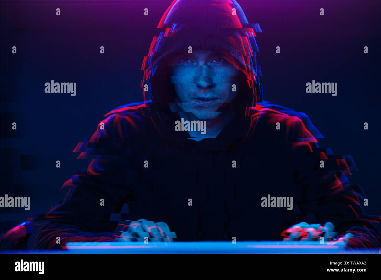 Hacker in the hood working with computer typing text in dark room. Image with glitch effect ...