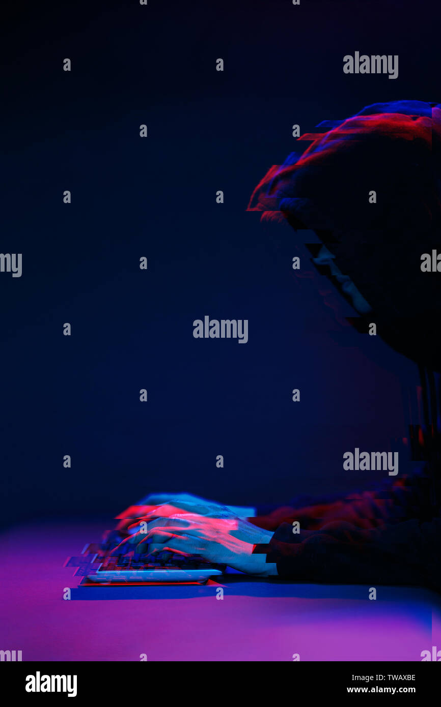Hacker In The Hood Working With Computer Typing Text In Dark Room Image With Glitch Effect