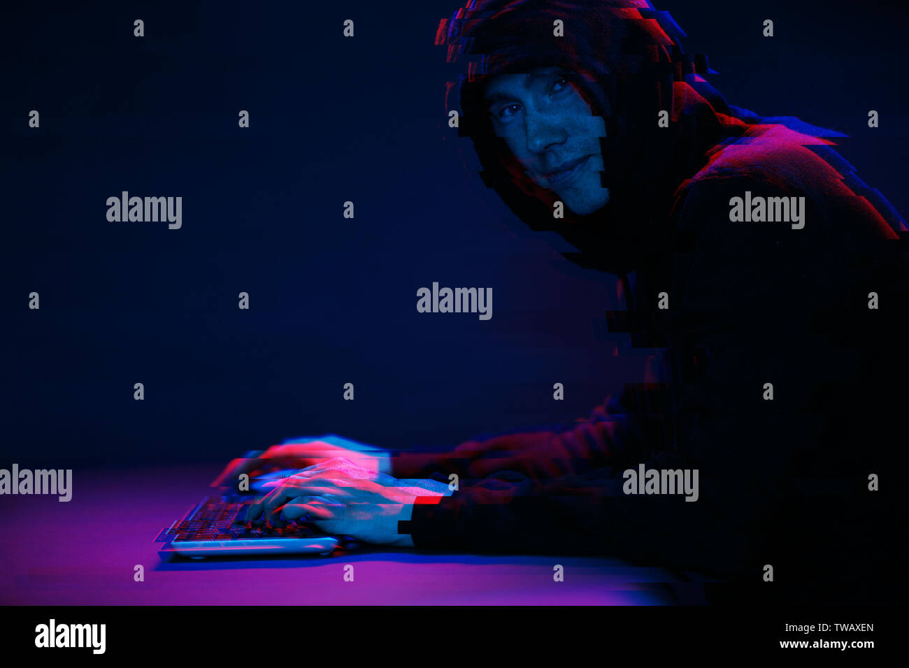 Hacker In The Hood Working With Computer Typing Text In Dark Room Image With Glitch Effect