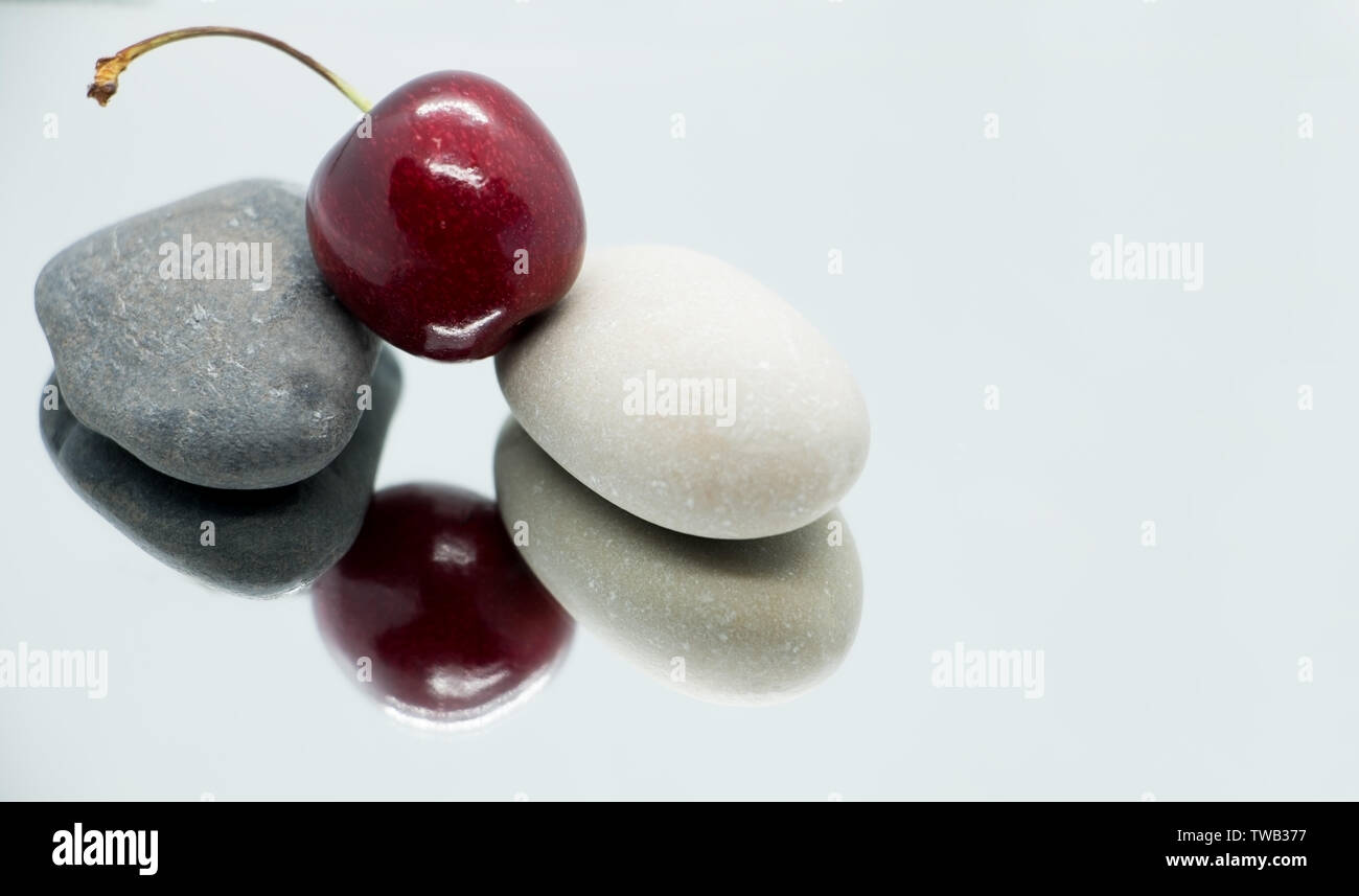 Close up of sweet fresh red cherry and stones on the mirror surface ...