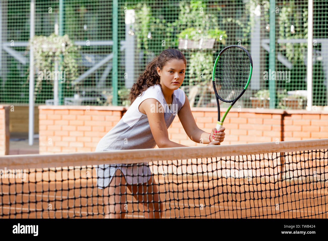 Girl teenager with long curly hair with a racket in his hands. Girl ...