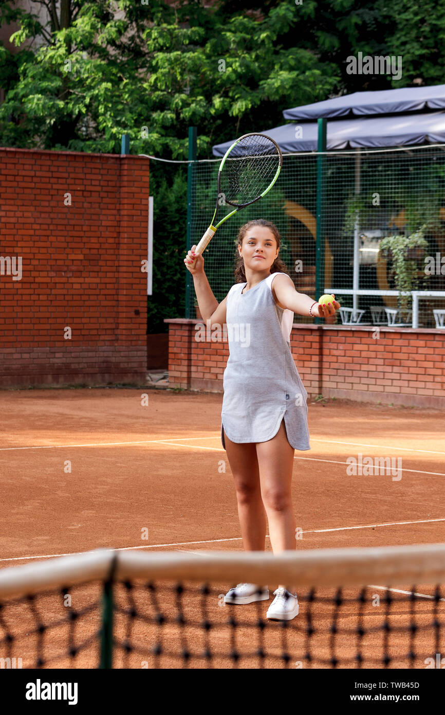 Girl teenager with long curly hair with a racket in his hands. Girl ...