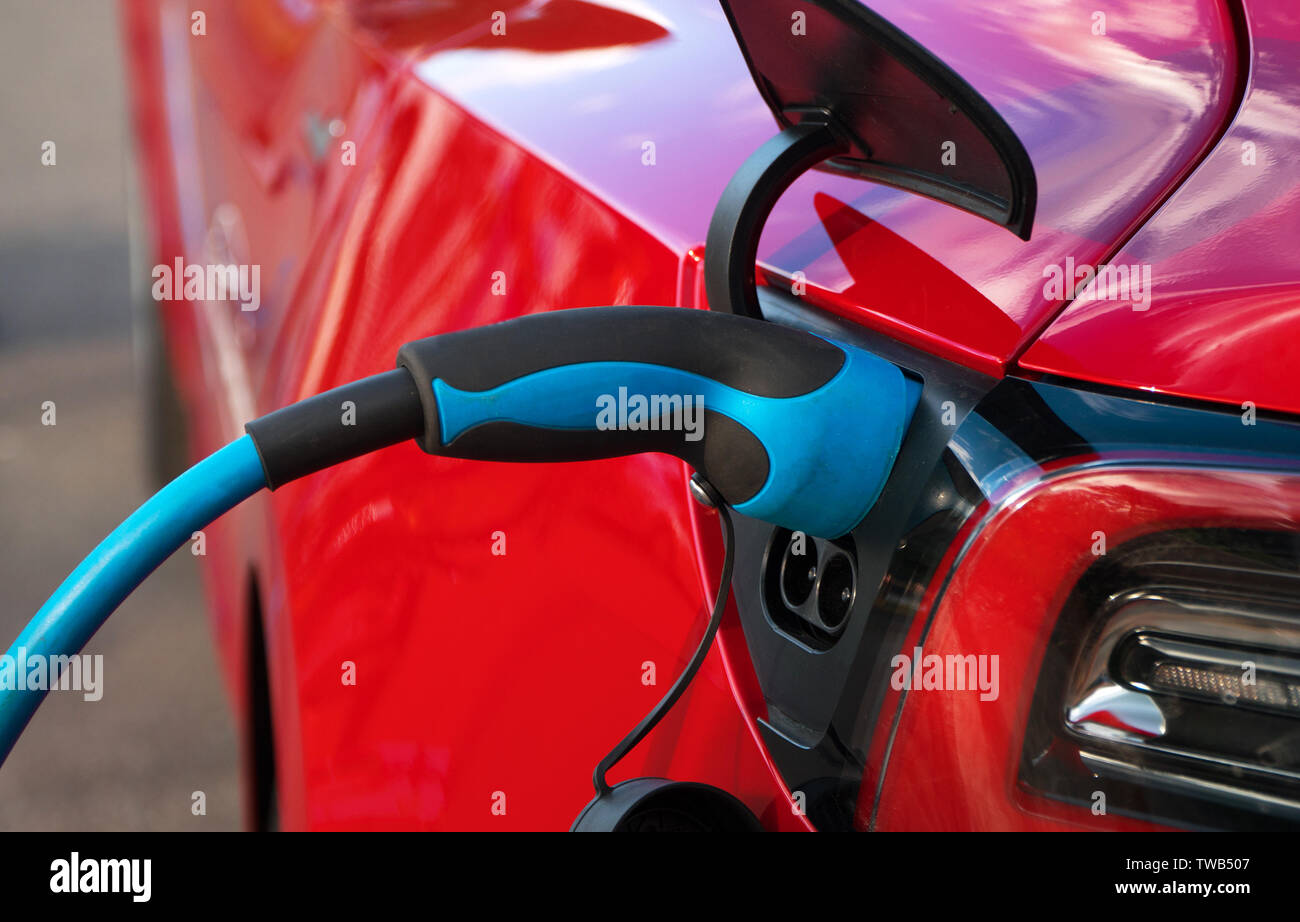 Electric plug charging red sports electric car Stock Photo - Alamy