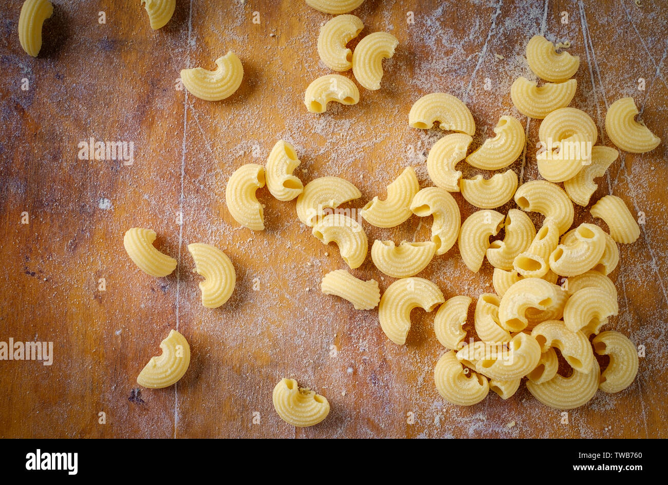 fresh Elbow pasta made at home on a wooden table with flour. Top view ...