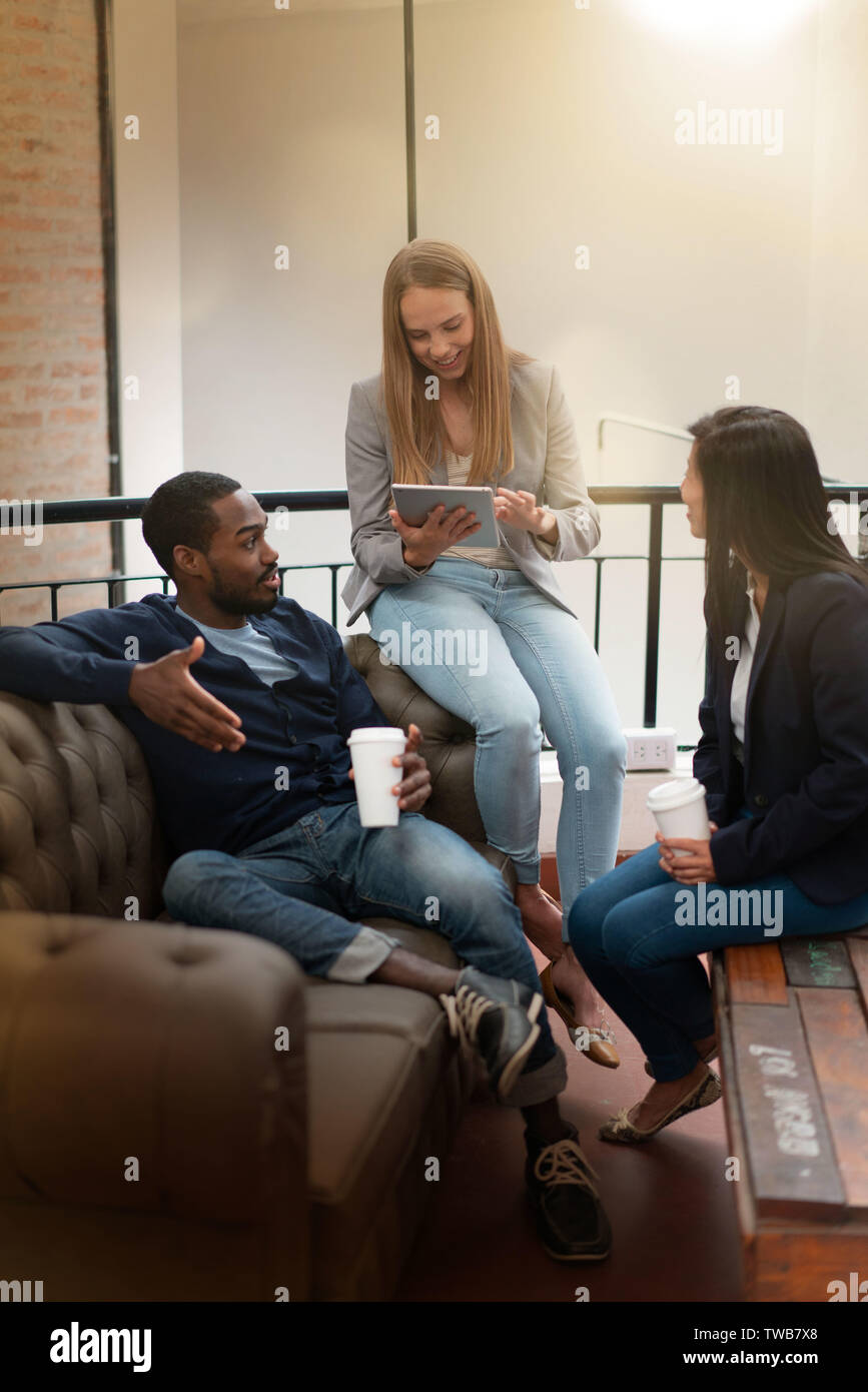 Attractive co workers talking sitting on sofa with tablet Stock Photo ...