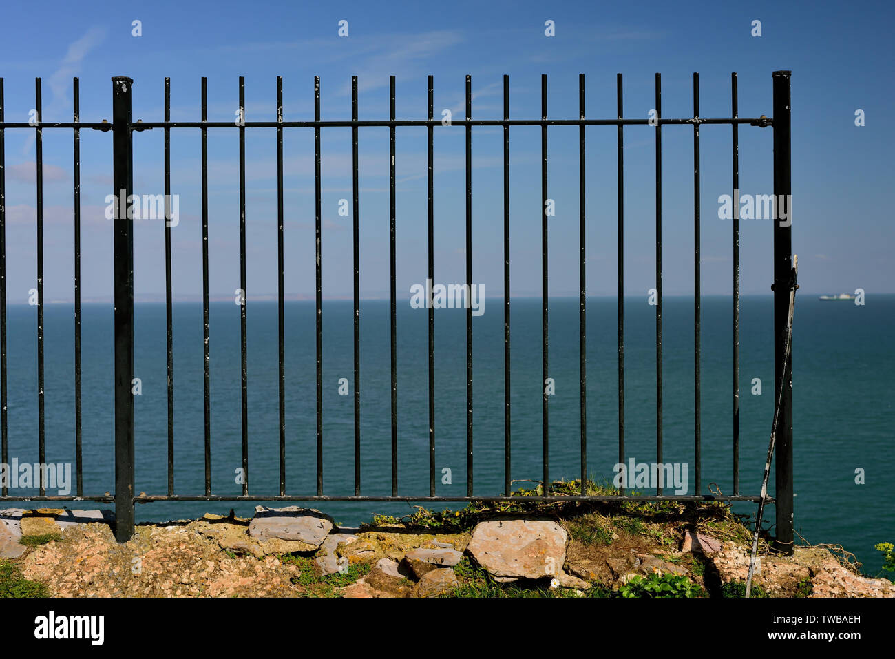 Metal railings guarding a sudden drop along a cliff edge, looking ...