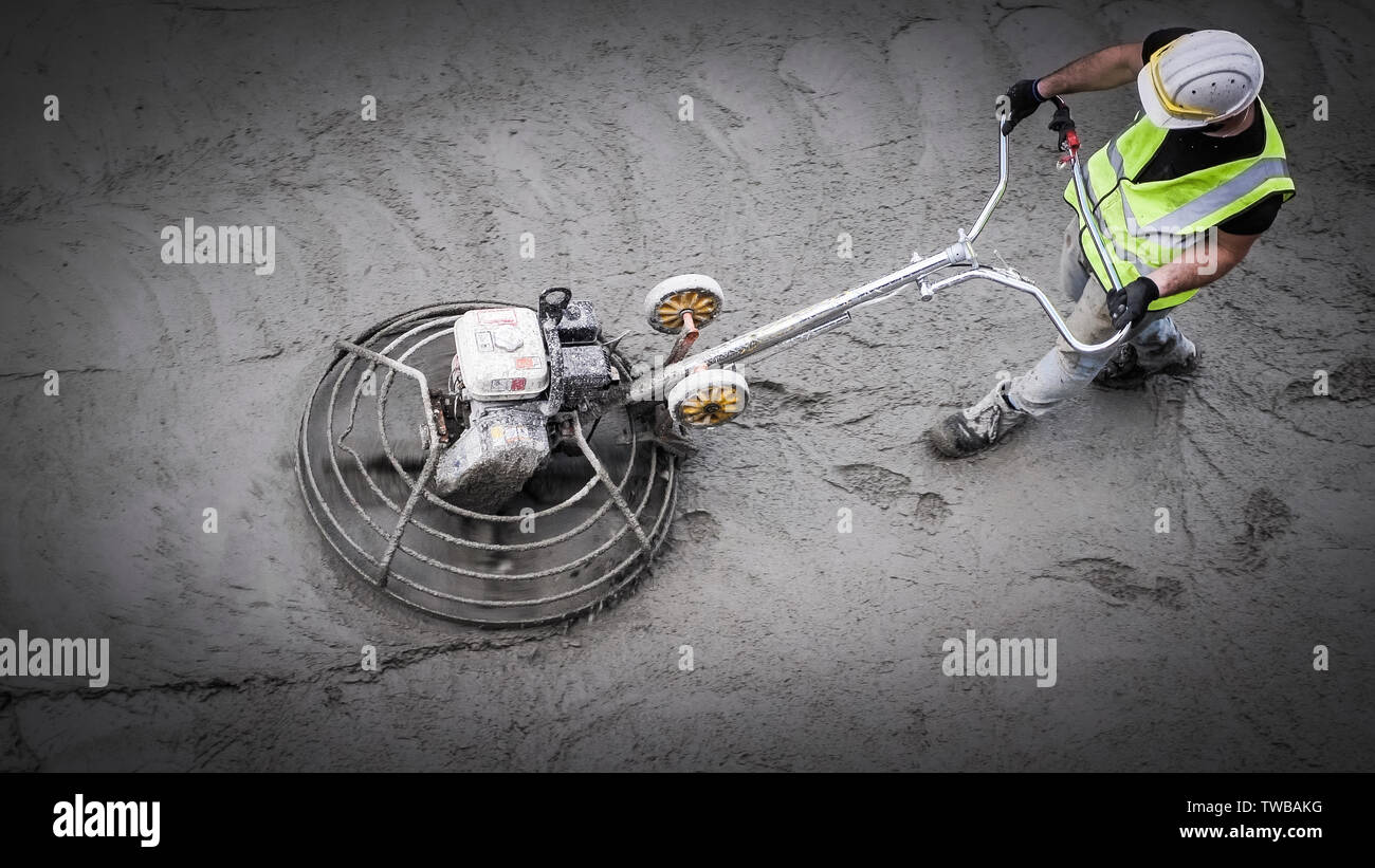 Construction worker levelling and troweling fresh concrete on ...