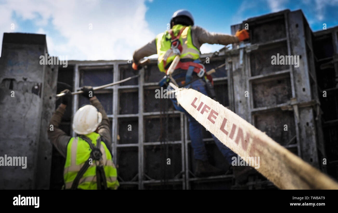 Two Construction workers connected with a safety harness to a life line ...