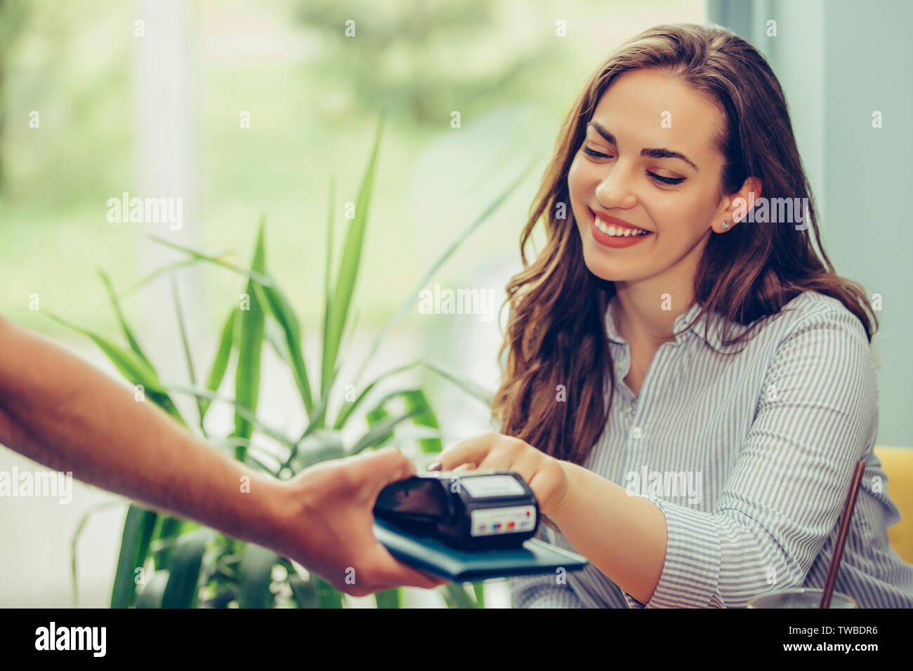 Young woman paying by credit card at cafe. Woman entering security pin ...