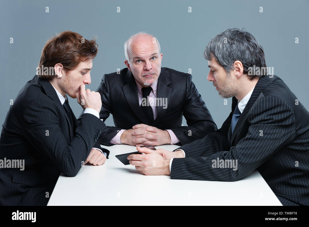 Three businessmen having a serious discussion during a meeting seated ...