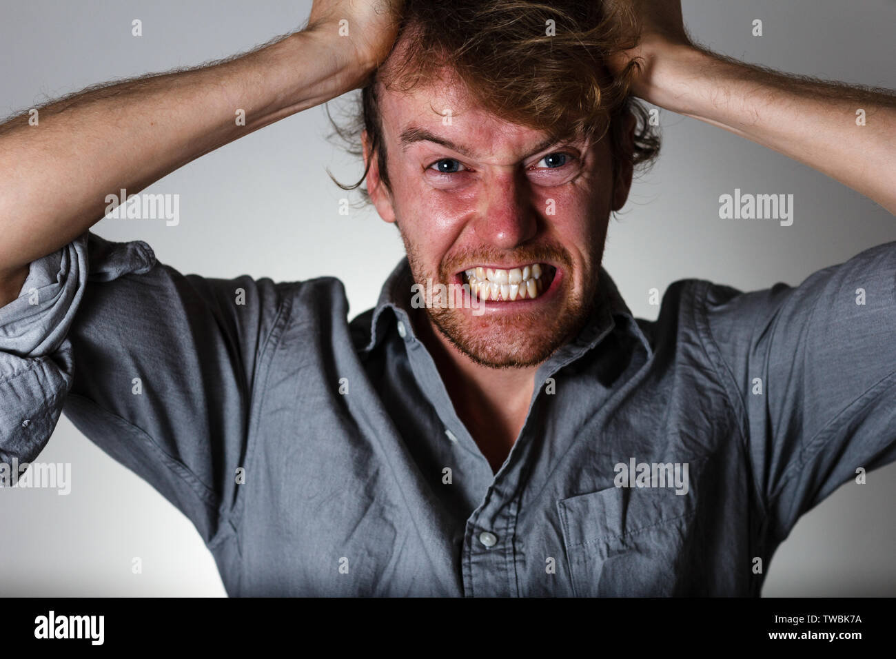 Angry young man on gray background Stock Photo - Alamy