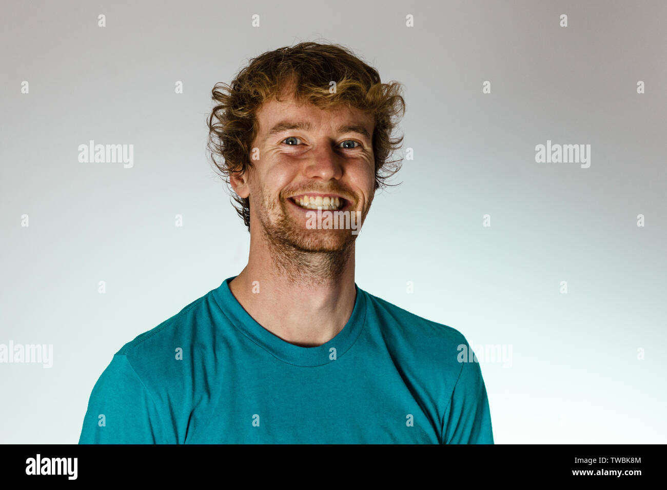 Smiling in delight from young man on gray background Stock Photo - Alamy