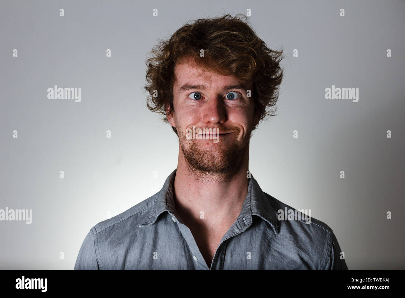 Smiling in delight from young man on gray background Stock Photo - Alamy