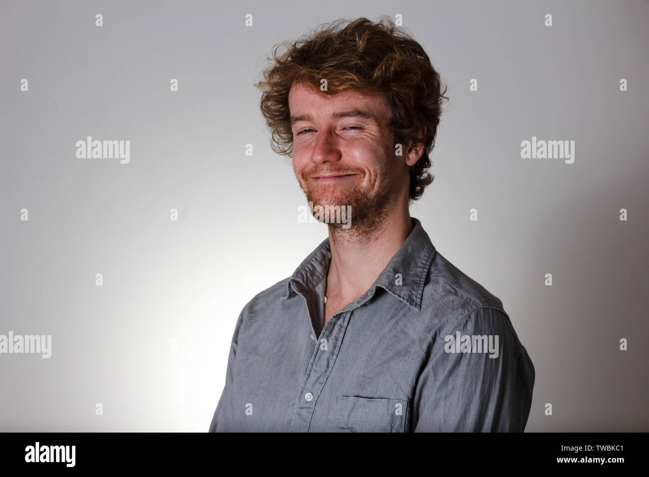 Smiling in delight from young man on gray background Stock Photo - Alamy
