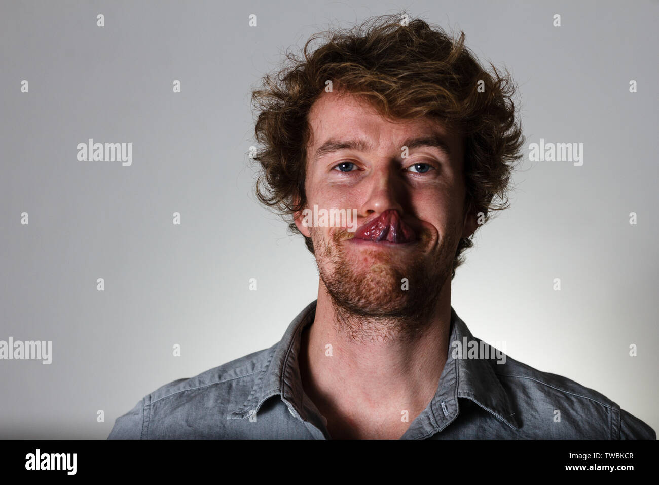 Funny, silly expression of young man on gray background Stock Photo - Alamy
