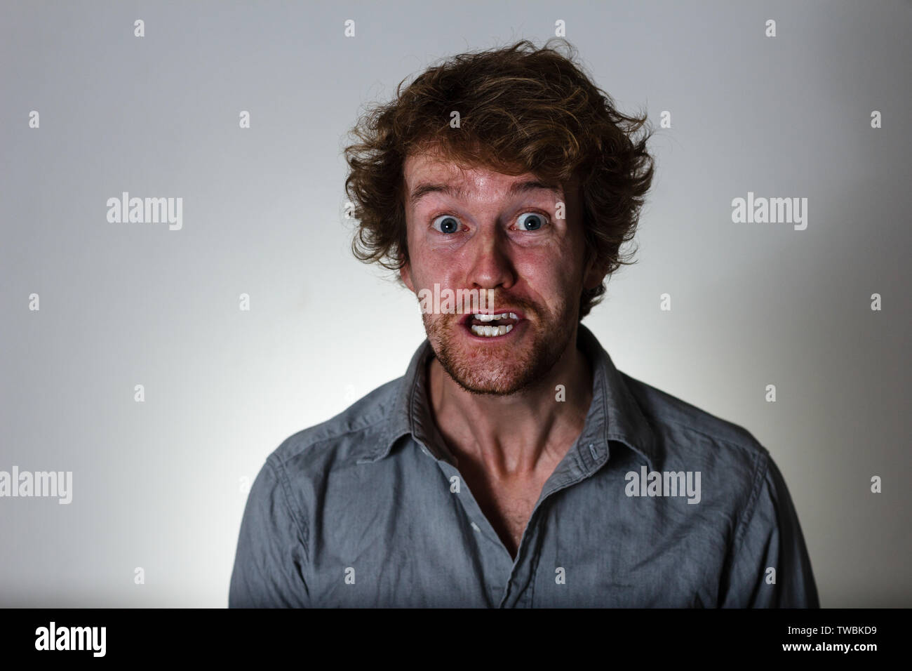 Weird expression from young man on gray background Stock Photo - Alamy