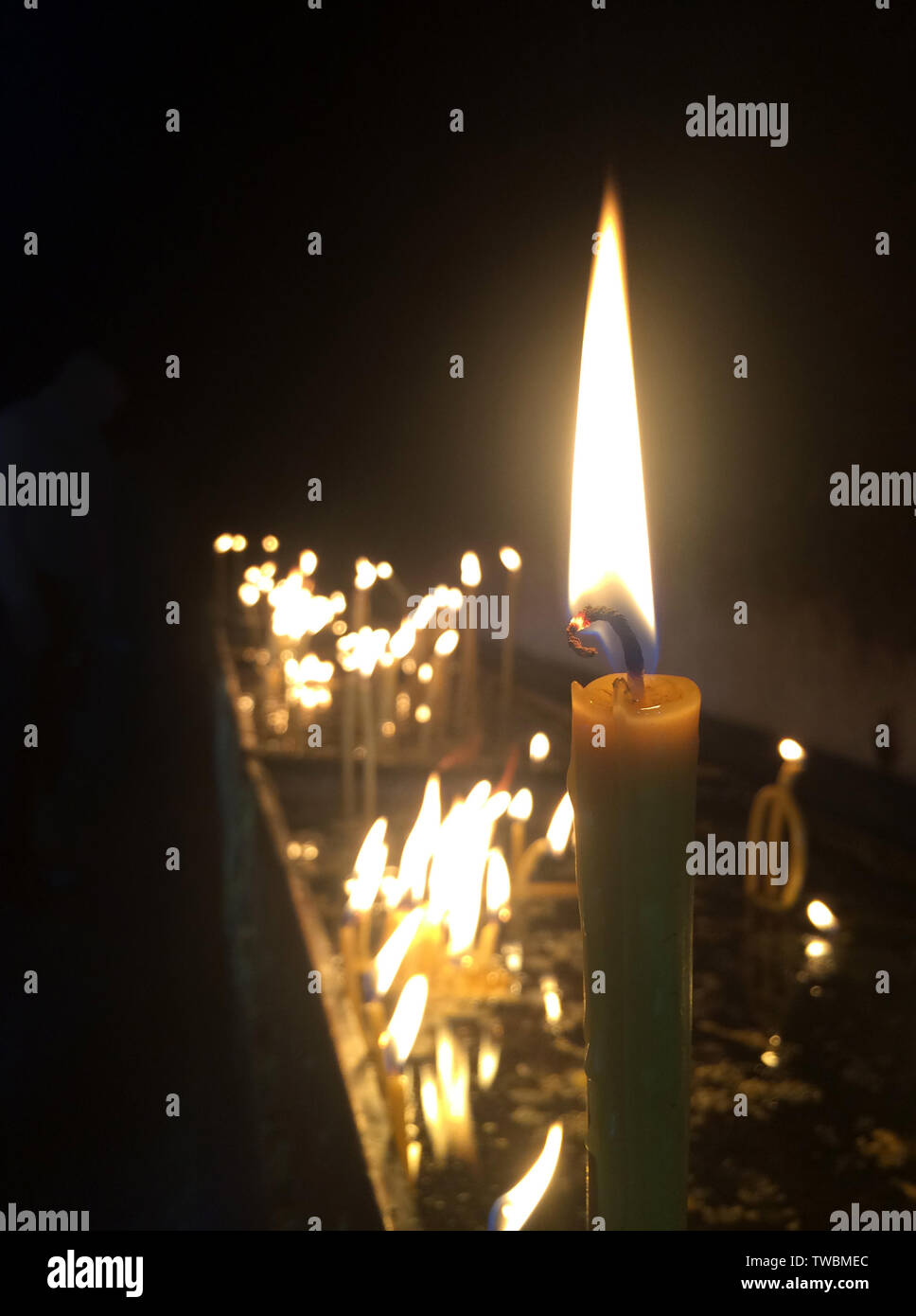 Many candles burning in a dark room Stock Photo - Alamy