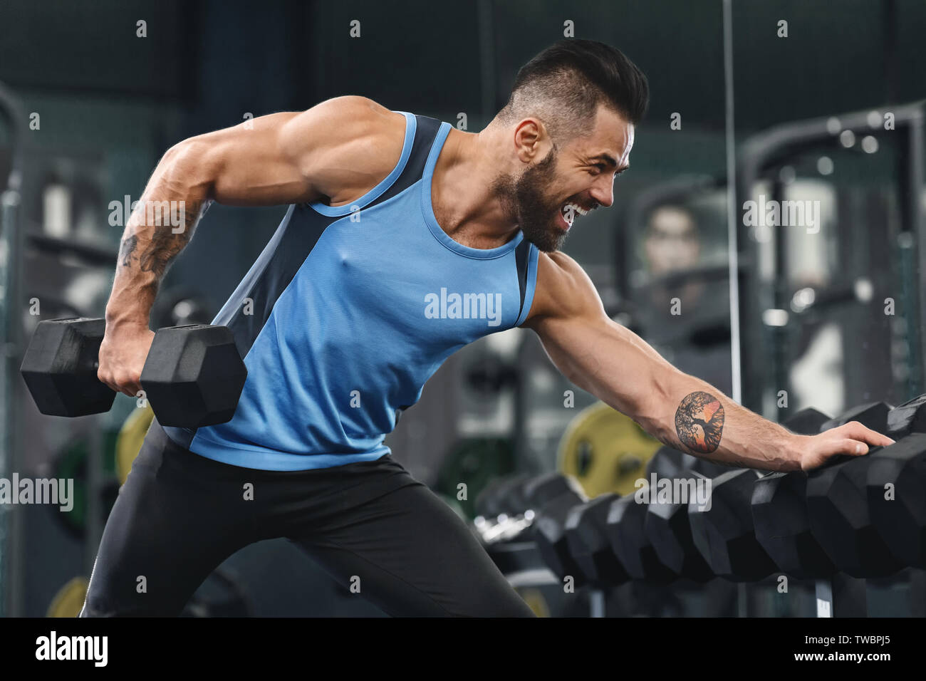 Hard strength workout. Athlete lifting dumbbell, exercising at ...