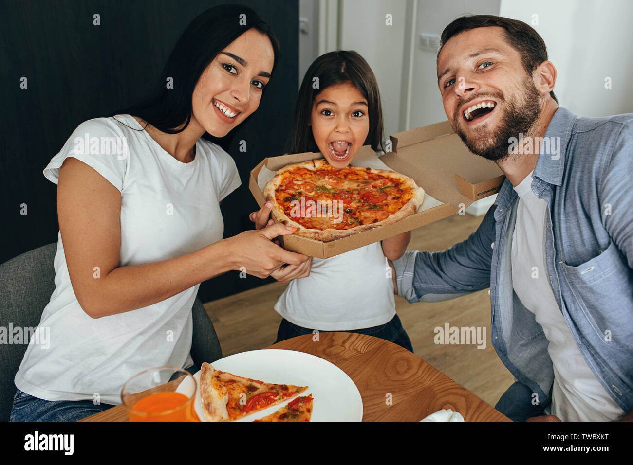 Family enjoying pizza lunch. Little girl having fun with her family ...