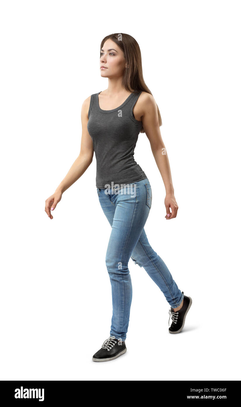 Young attractive woman in gray sleeveless top and blue jeans walking in ...