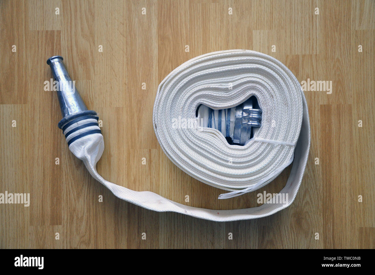 White rolled up fire extinguishing hose with coupling and nozzle ...