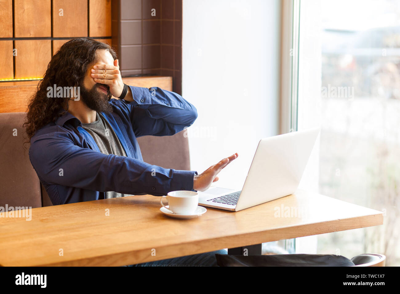 Scared bearded young man freelancer in casual style and long curly hair ...